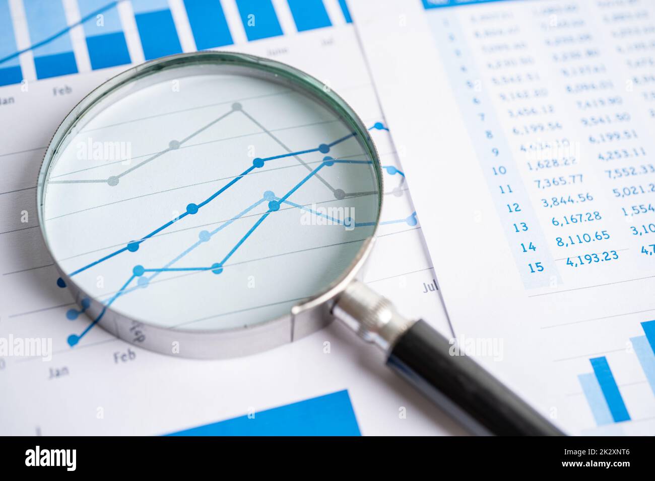 Magnifying glass on chart graph spreadsheet paper. Financial ...