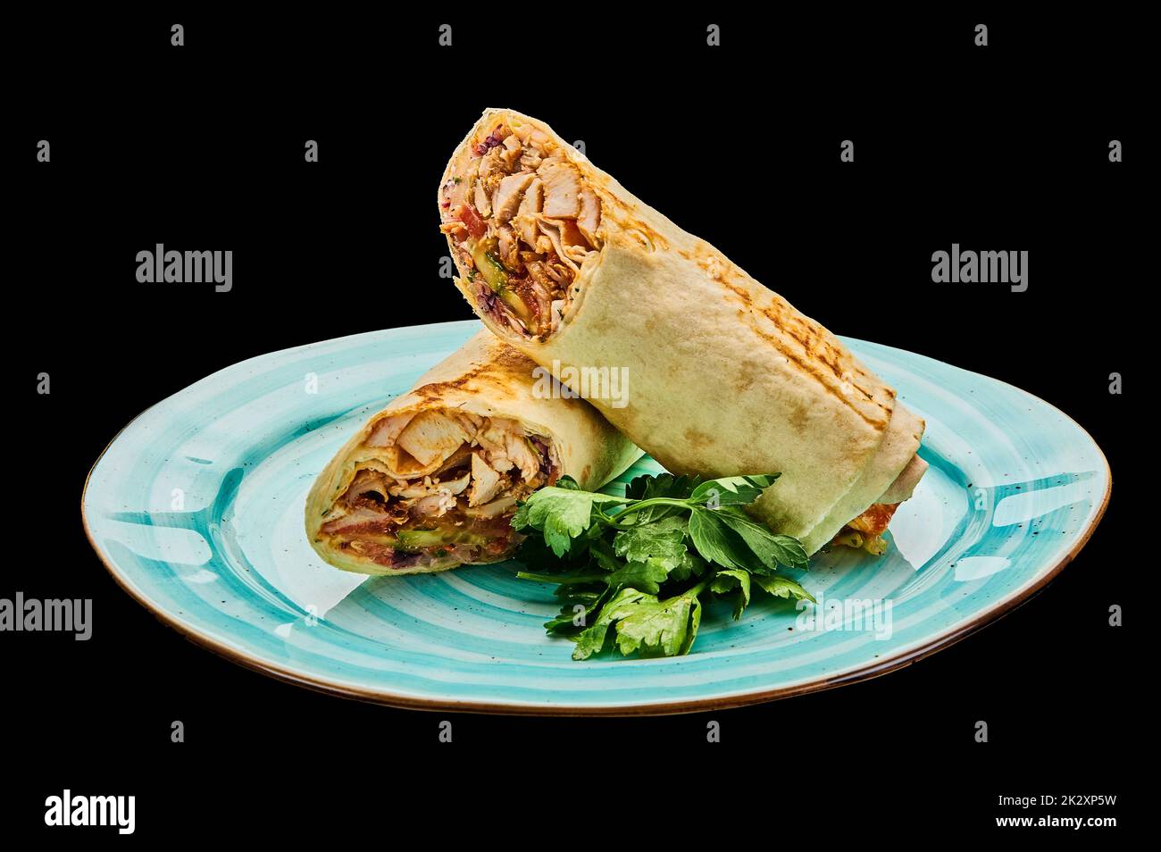 Shawarma of chicken in garlic lavash lies on a plate on a black ...