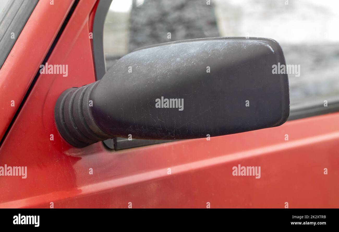 Side left black plastic rearview mirror on a red car. Exterior side ...