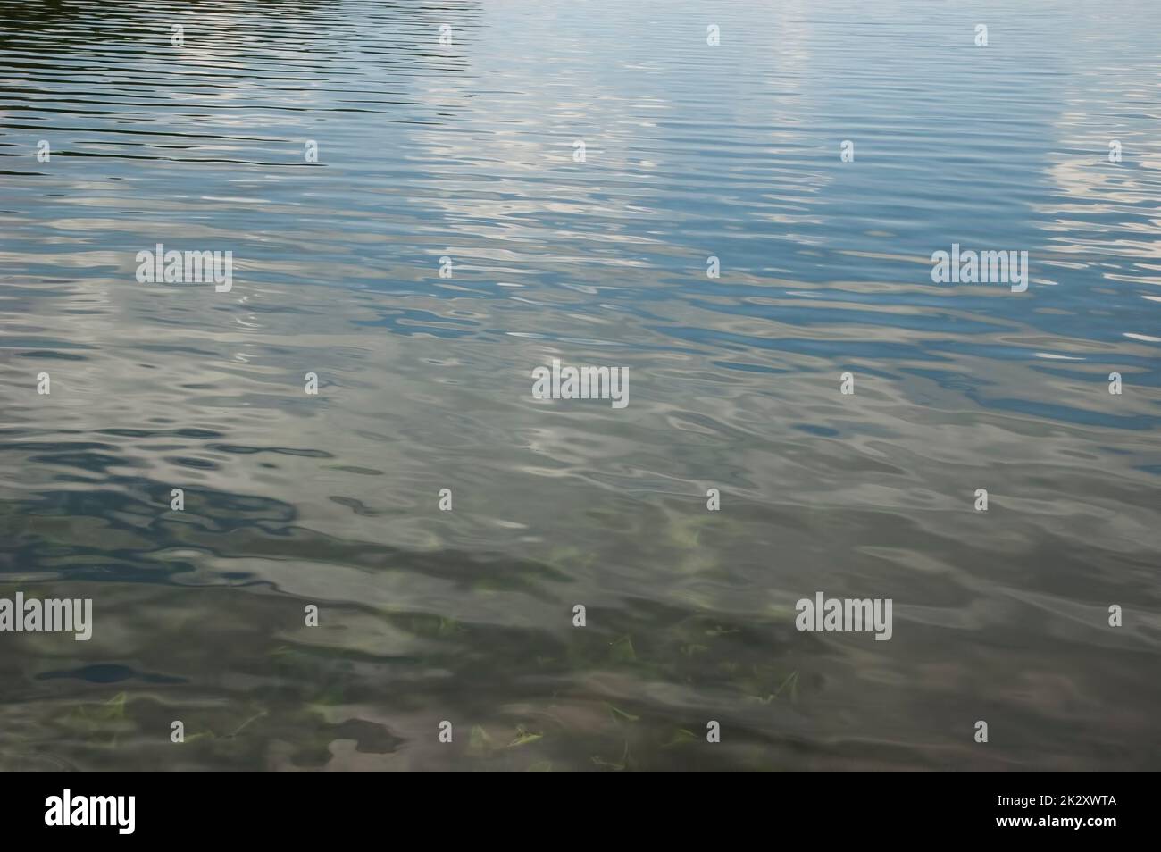 abstract background: a blue sky is reflected in the water with small ...