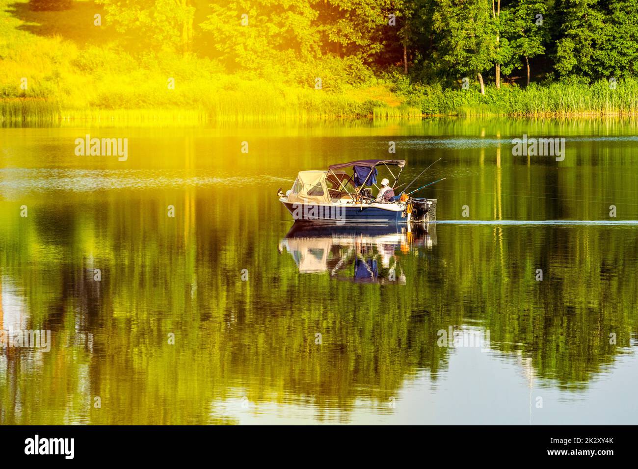 Fishing boat with a fisherman on lake while catching fish Stock Photo ...