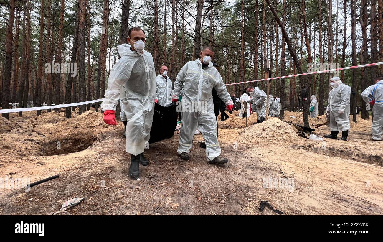 Experts work during the exhumation of bodies in the recently retaken ...