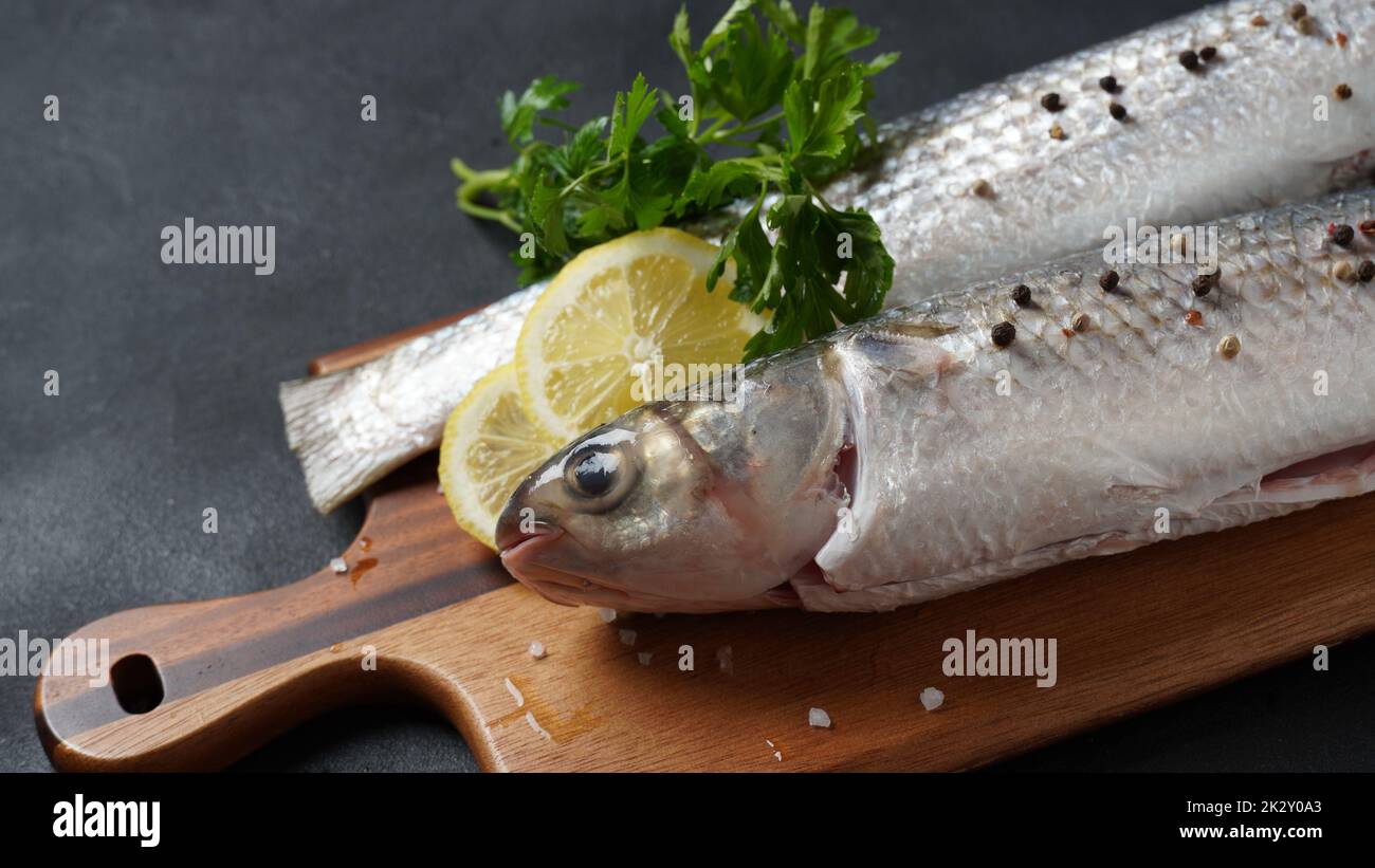 Seafood fresh mullet fish with lime, herbs and spices on a dark ...