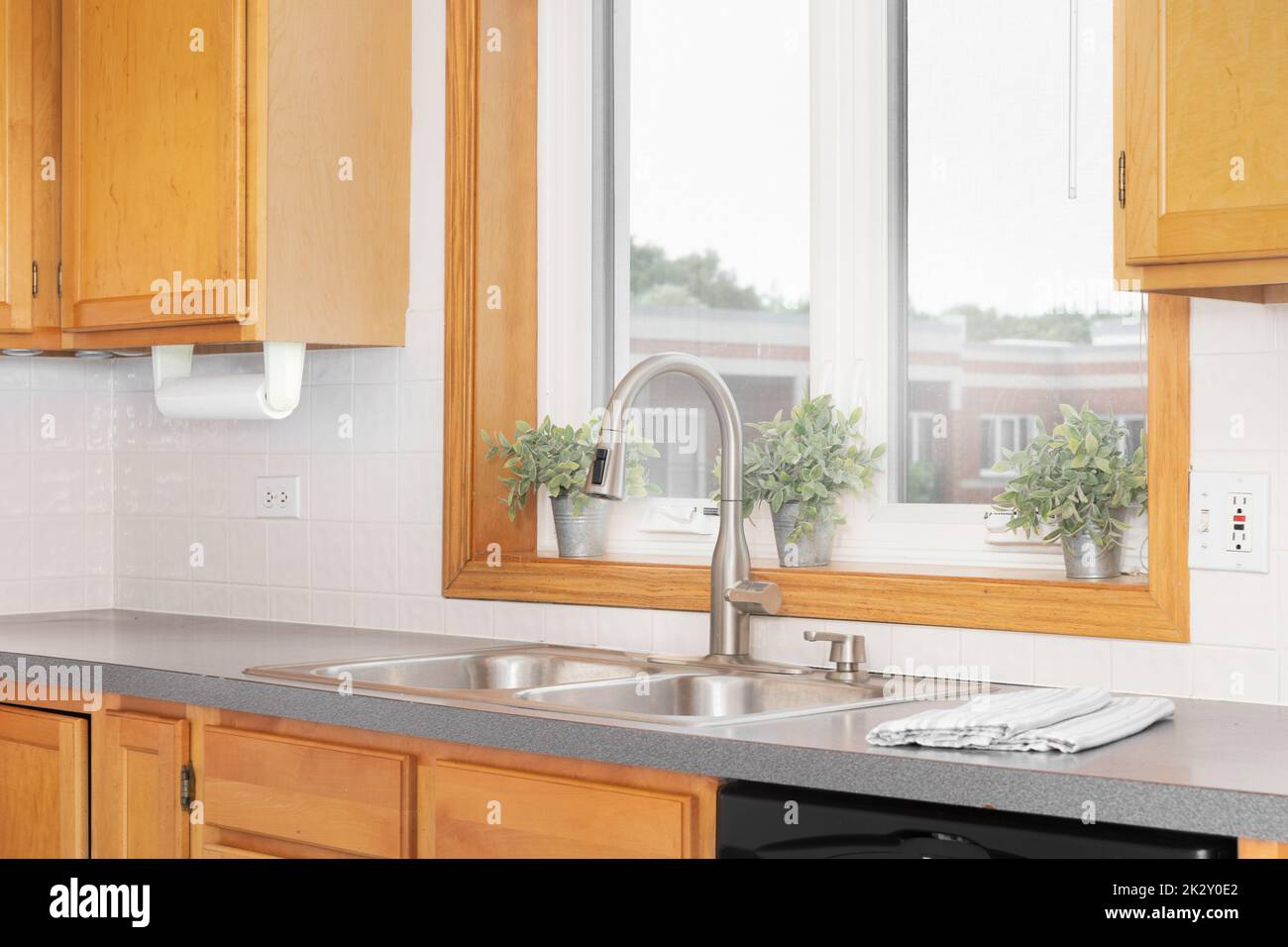 A kitchen sink detail shot with wood cabinets, stainless steel sink ...