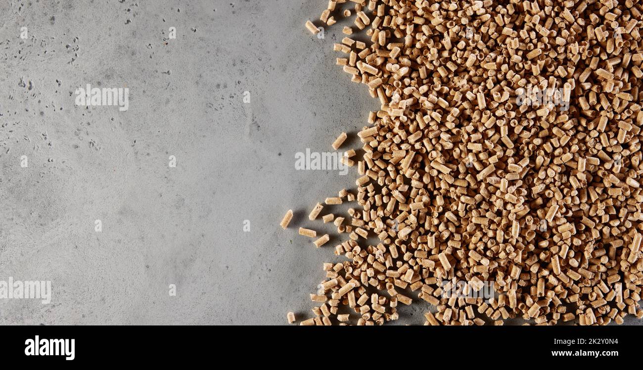 Pile of solid wood pellets scattered on gray surface as background ...
