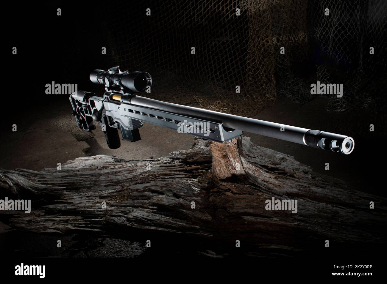 Bolt action rifle and scope on a log with netting behind Stock Photo ...