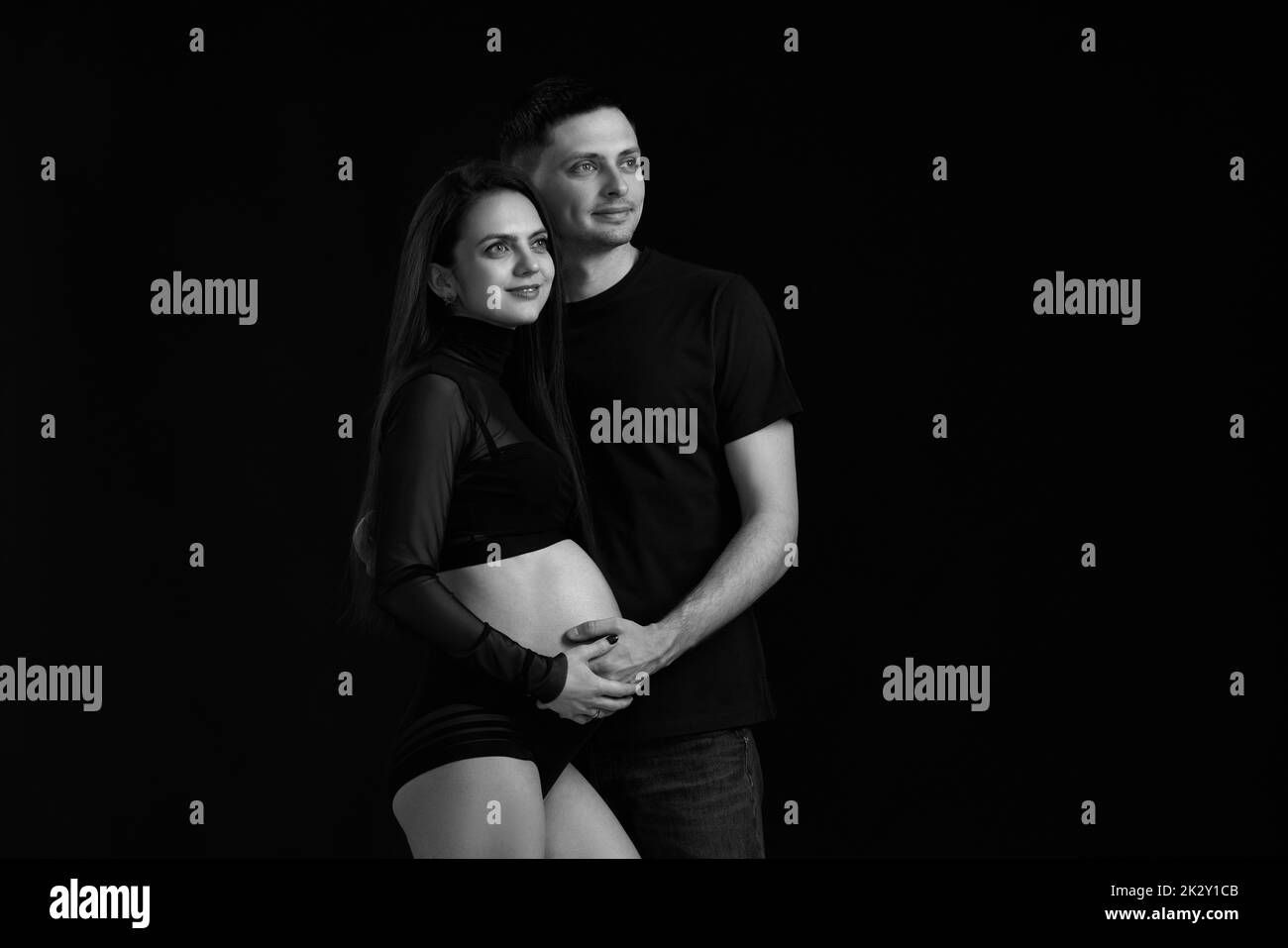 couple expecting baby and hugging on black background Stock Photo - Alamy