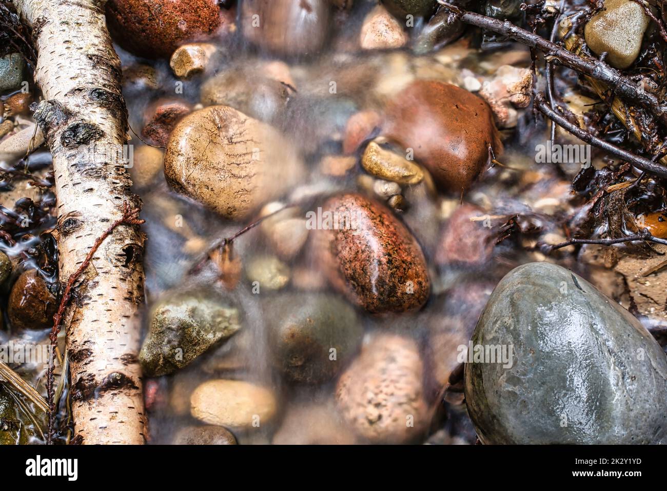A long exposure shot of colorful rocks under the water of the small ...