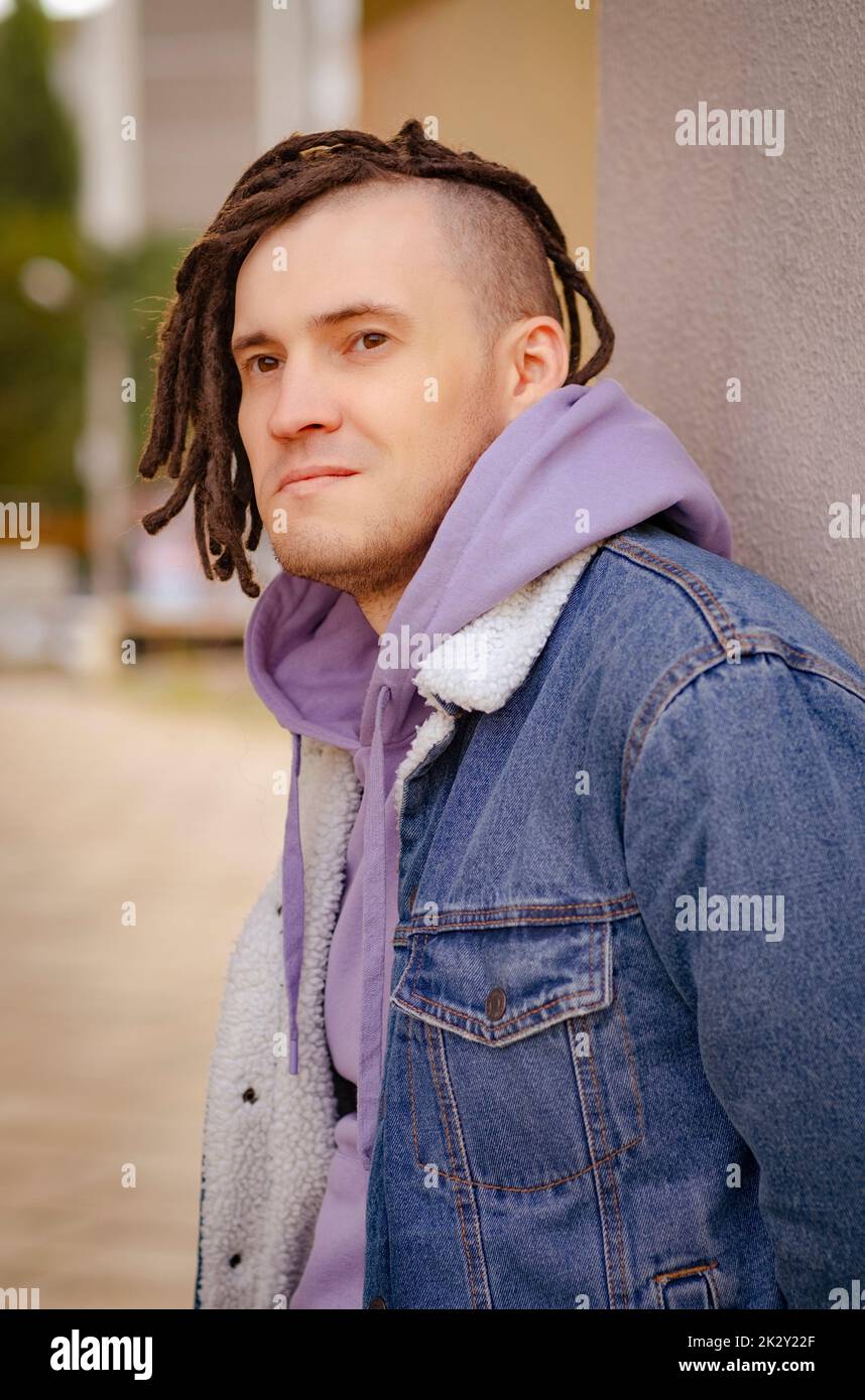 Portrait of young handsome man with dreadlocks posing, standing ...