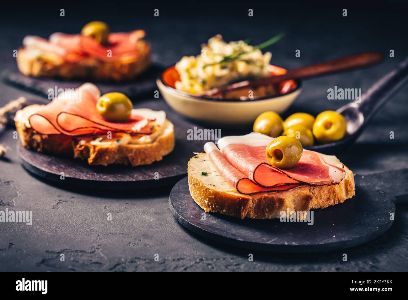 Roasted bread with garlic butter spread and serano ham and olive Stock ...