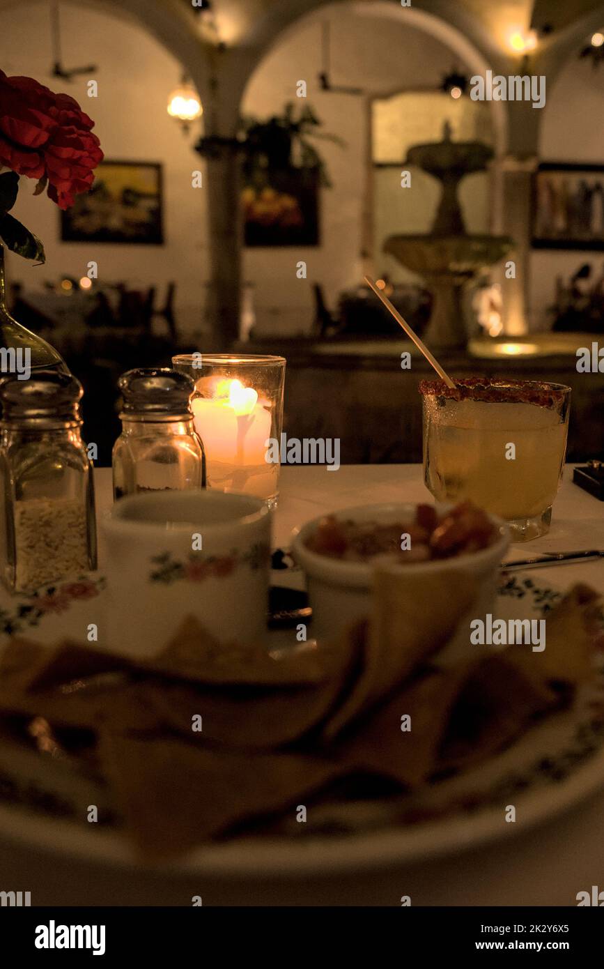 Chips and salsa with Mexican alcoholic drink next to candle at romantic ...