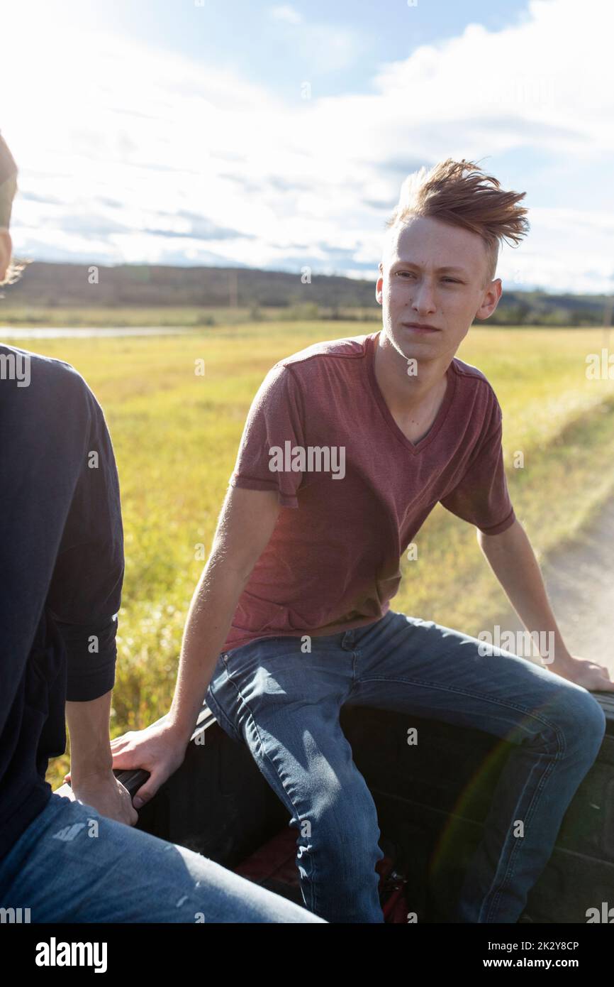 Young male farmer riding in pickup truck bed on sunny farm Stock Photo ...