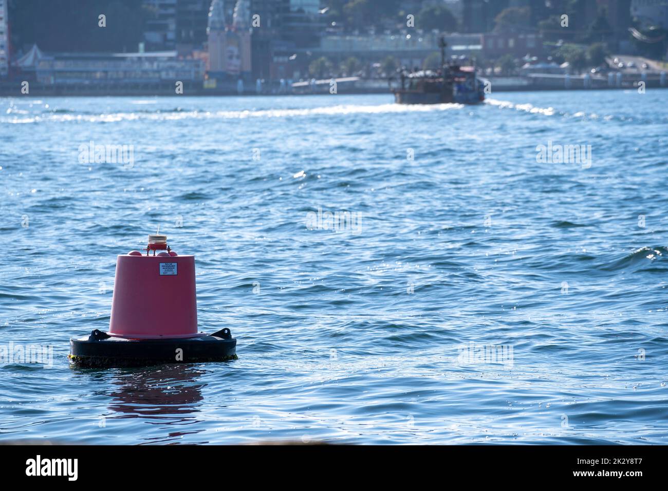 The red buoy floating on water with city background Stock Photo - Alamy