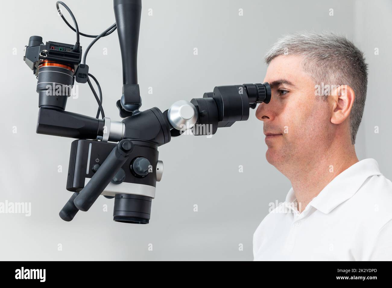 Dentist using dental microscope treating patient teeth at dental clinic ...
