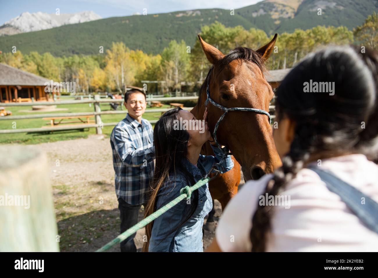 Happy woman kissing horse in sunny mountain ranch paddock Stock Photo ...