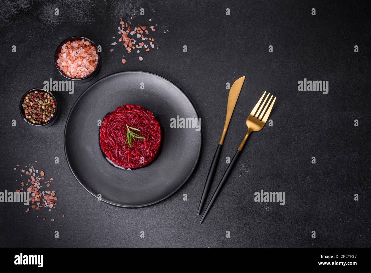 Cooked grated beetroot formed as a cylinder and ready dish on a black ...