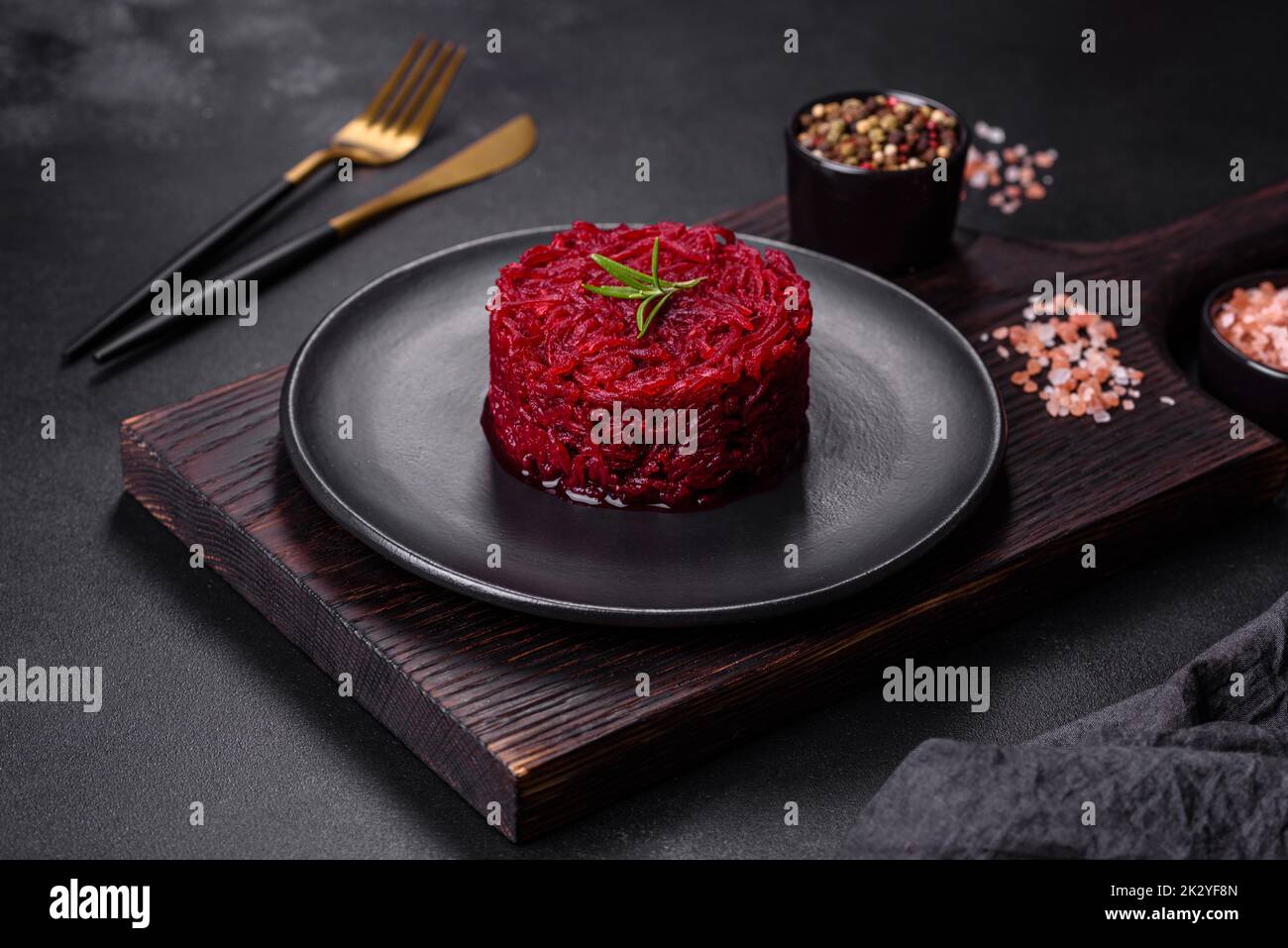 Cooked grated beetroot formed as a cylinder and ready dish on a black ...