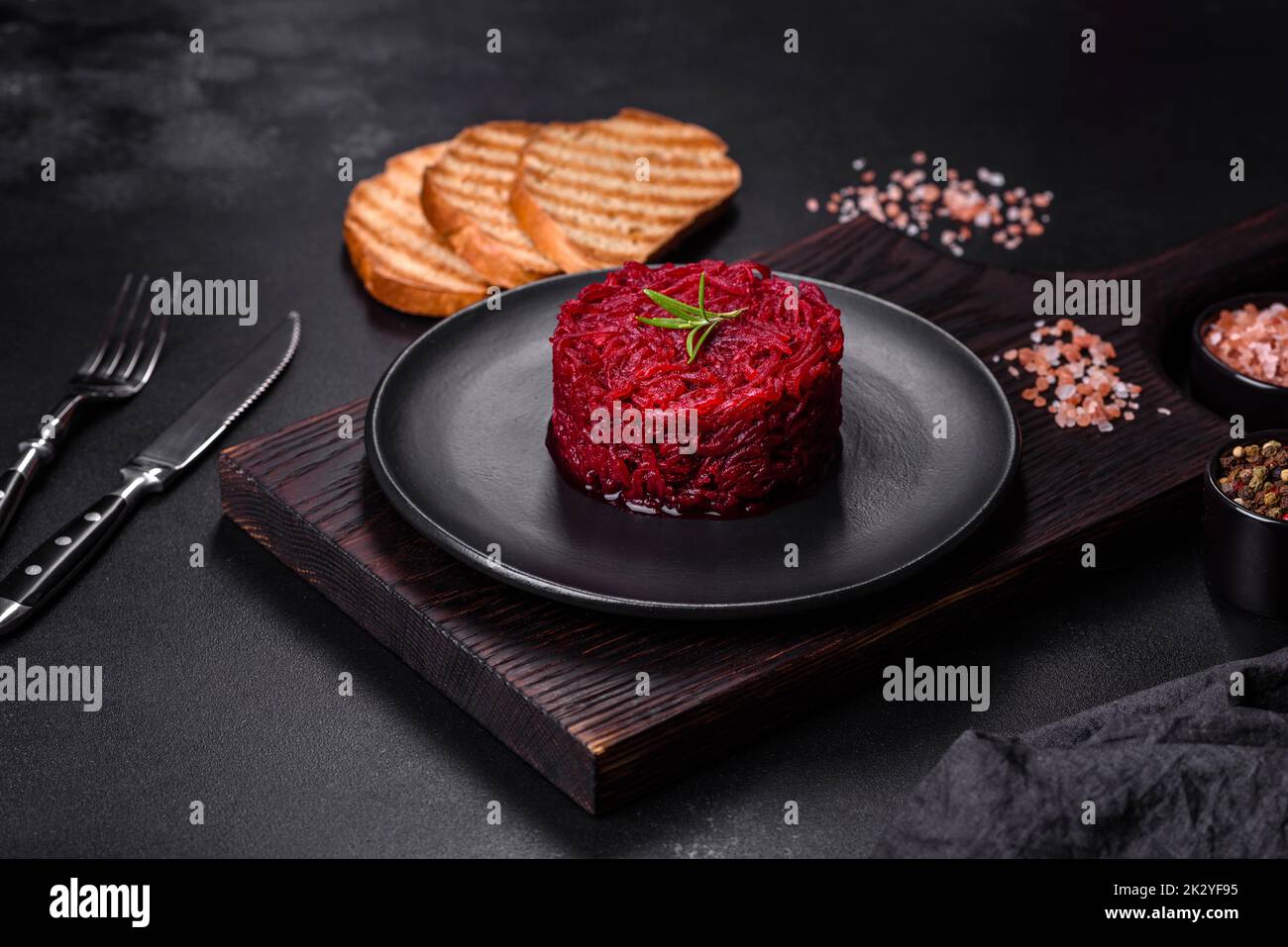Cooked grated beetroot formed as a cylinder and ready dish on a black ...