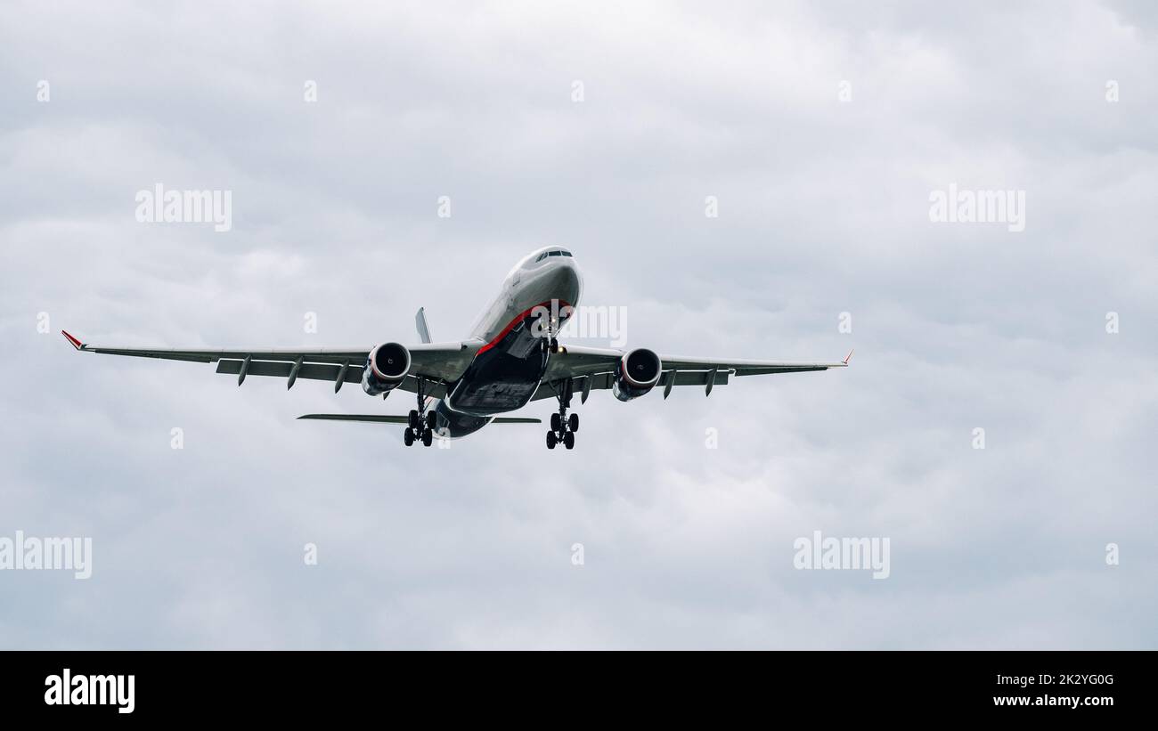 Passenger plane comes in for landing in cloudy weather Stock Photo - Alamy