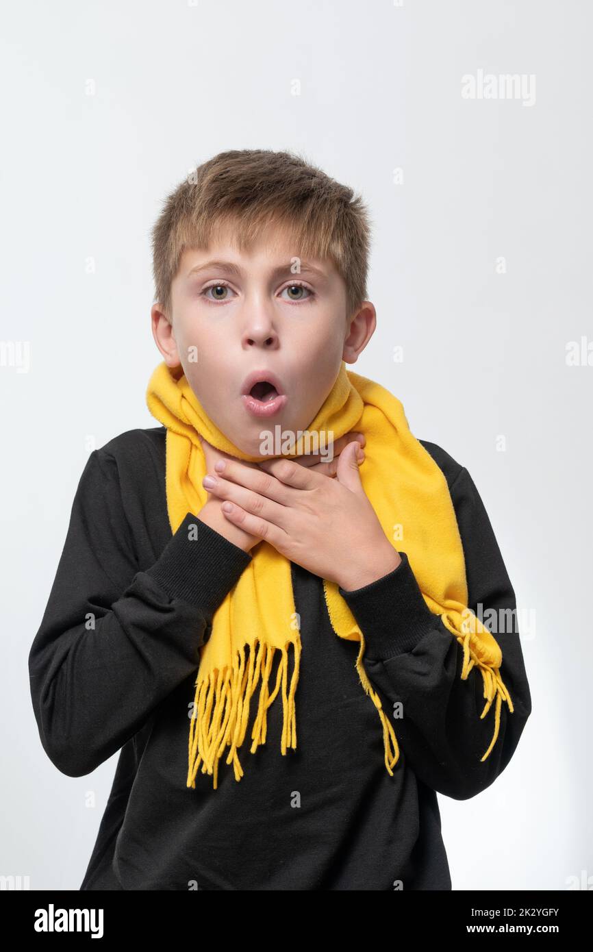 The child has a sore throat, the child is holding his throat with his ...