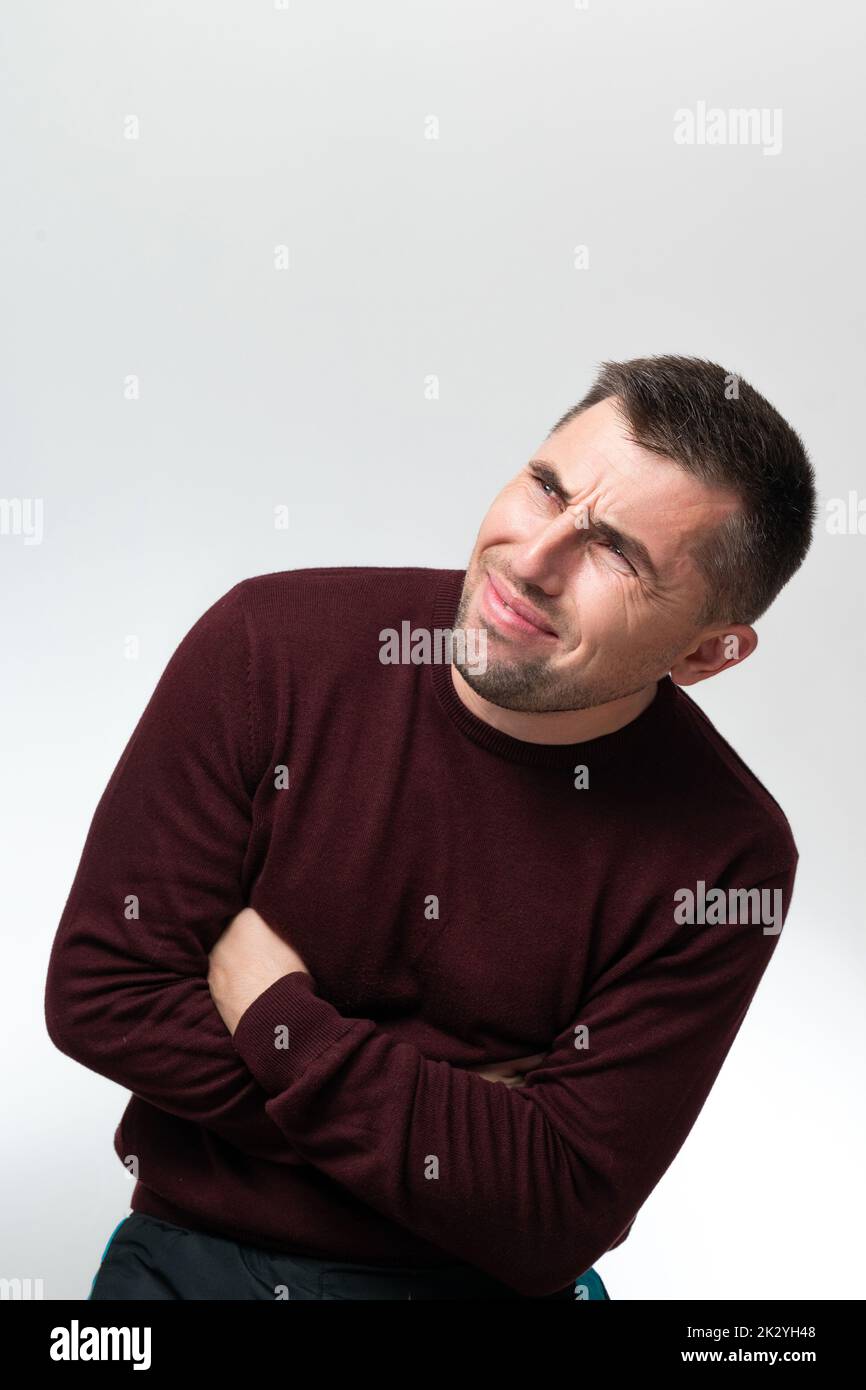 A man touches his stomach with two hands, on a white background with ...