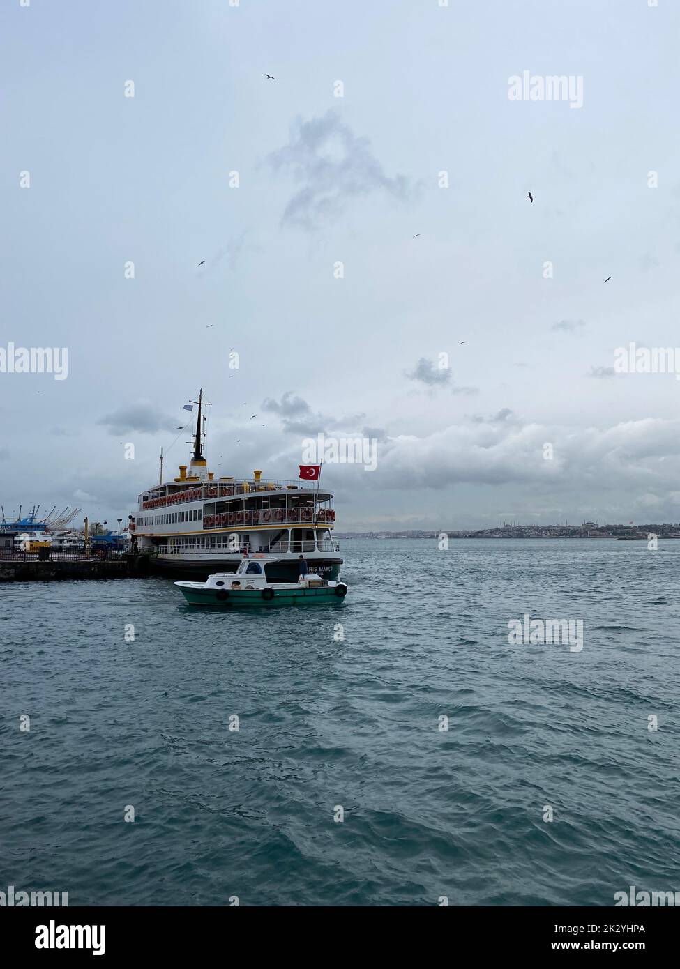 A vertical of an anchored ship with the Turkish flag and a boat in ...