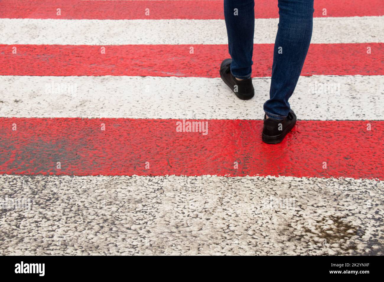 A man crosses the road at a pedestrian crossing, feet on the road, go ...