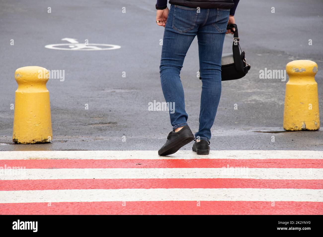 A man crosses the road at a pedestrian crossing, feet on the road, go ...