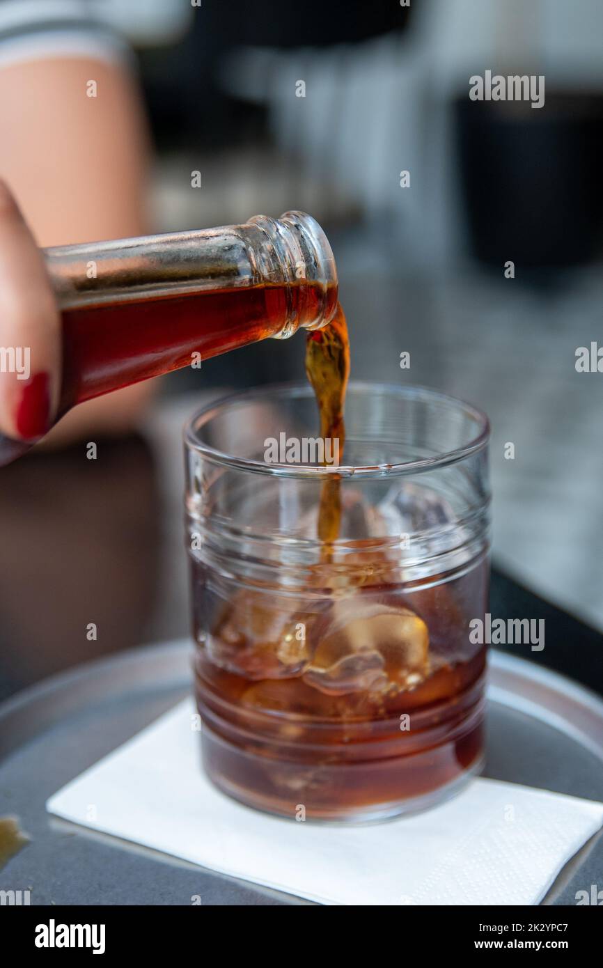 Pouring cold brew iced coffee in glass cup with ice cubes , coffee ...