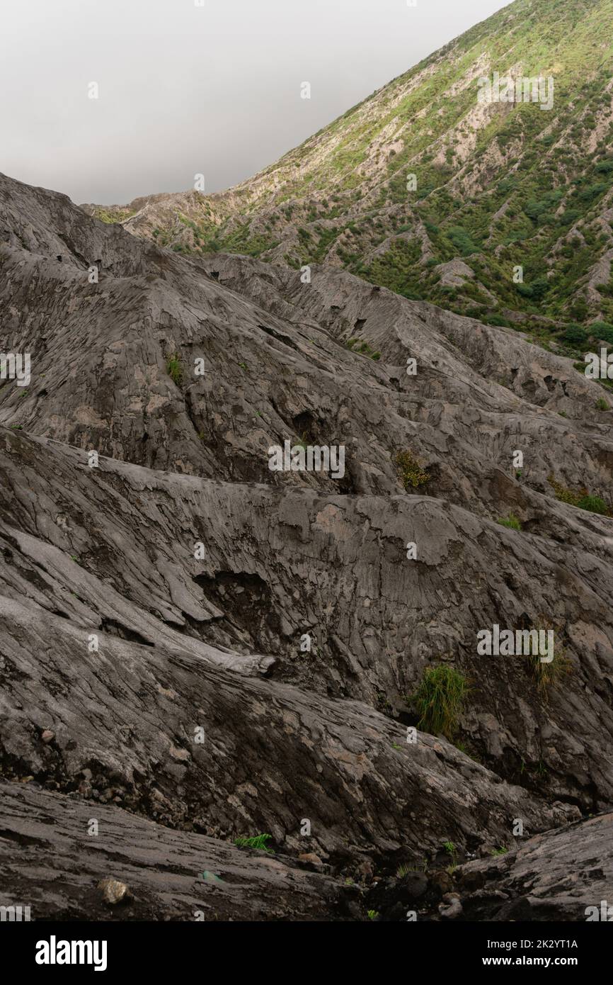 A vertical shot of an active volcano and black lava fields in Bromo ...