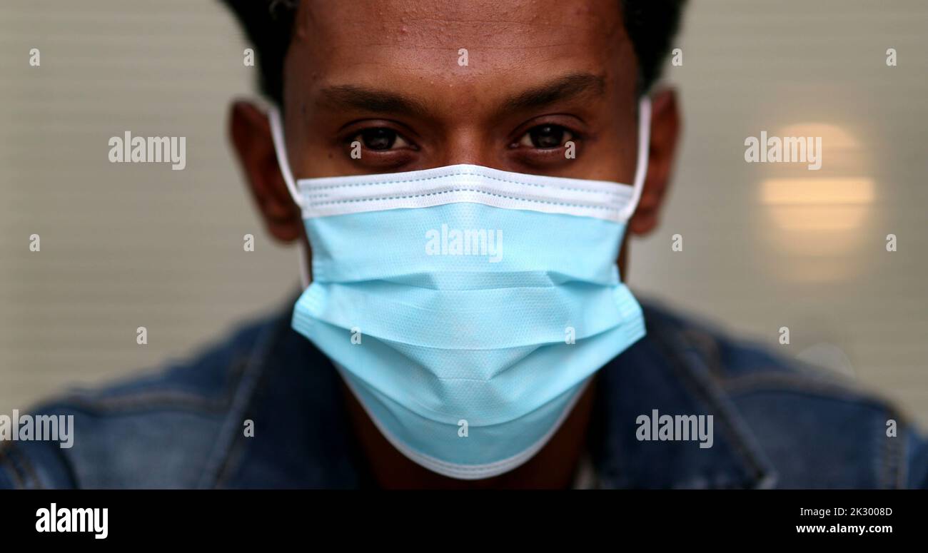 African man wearing covid-19 face mask. Person putting surgical mask ...