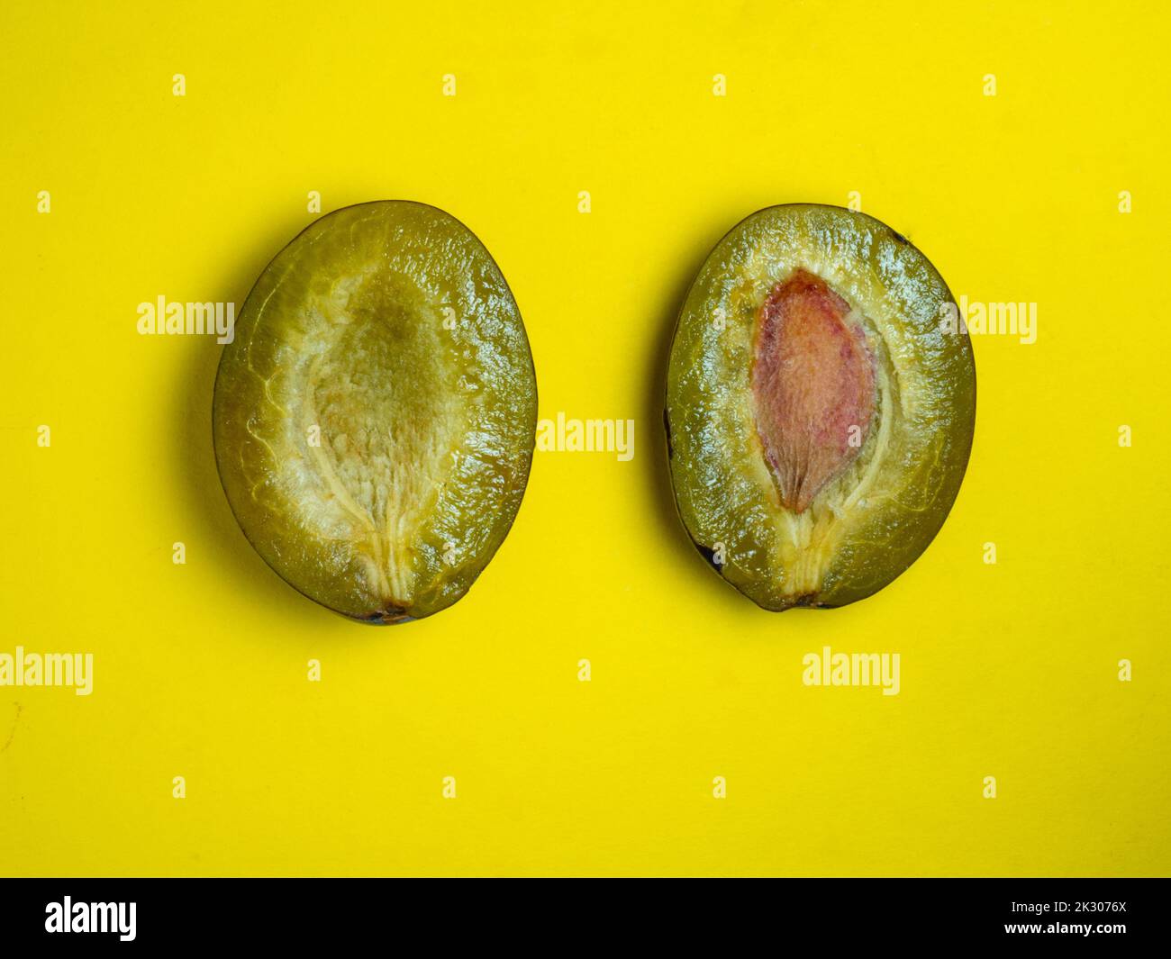 Plums on a yellow background. Juicy sliced plum. Stone in yellow pulp ...