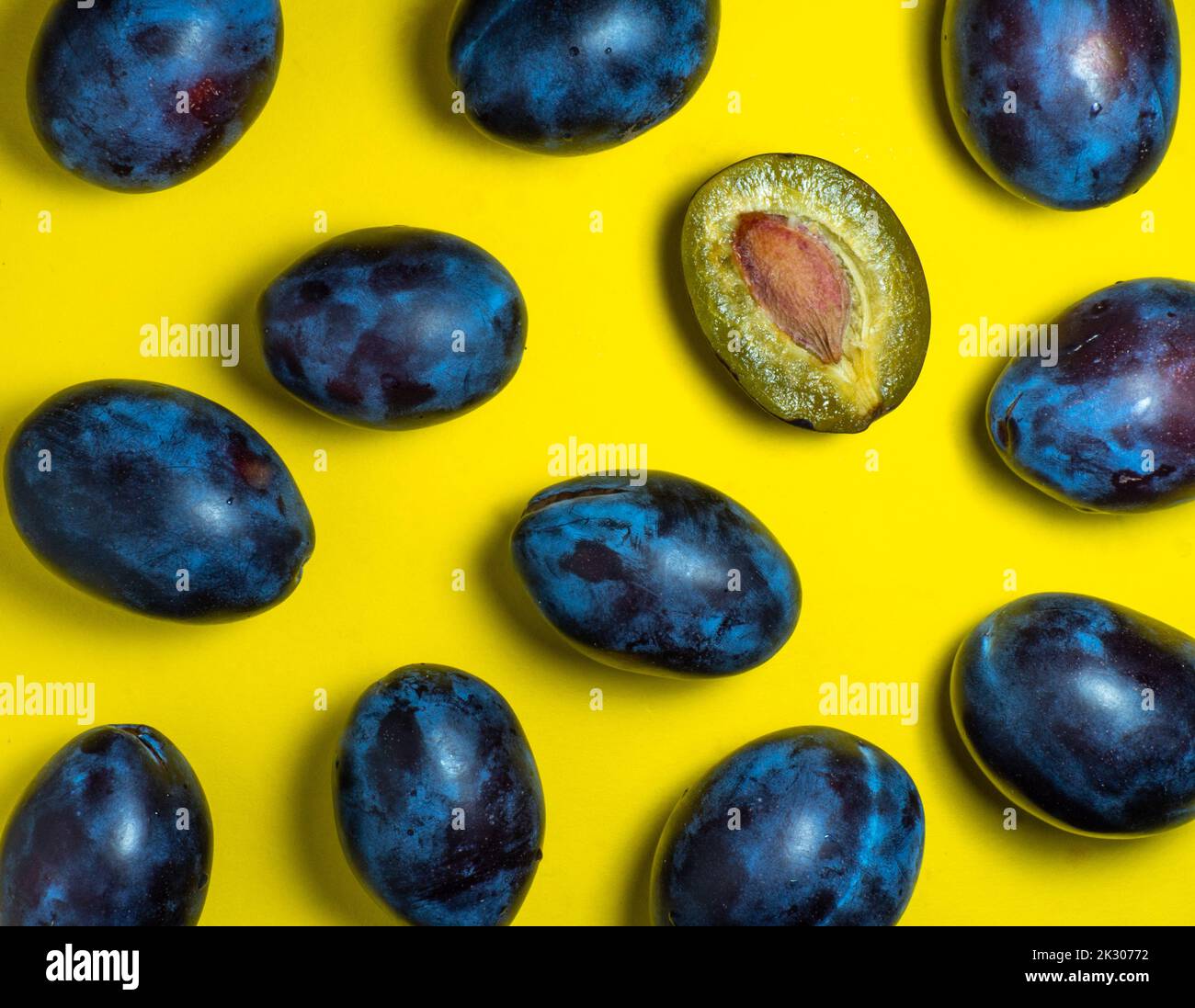 Plums on a yellow background. Juicy sliced plum. Stone in yellow pulp ...