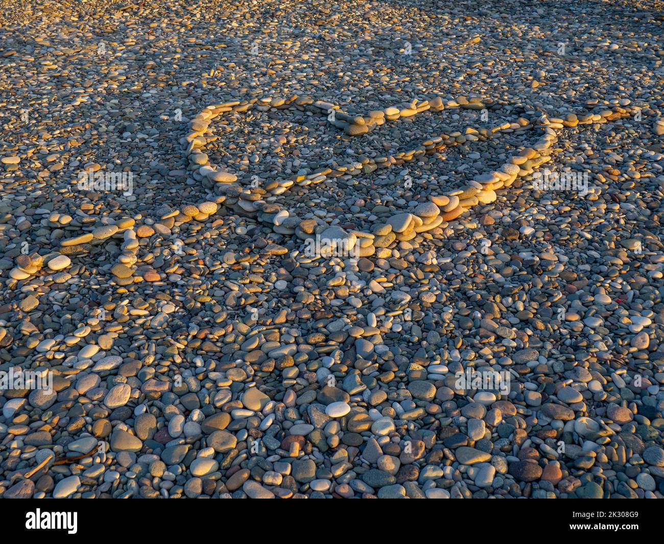 Heart laid out with stones on stones. Heart hit by an arrow. Love sign ...