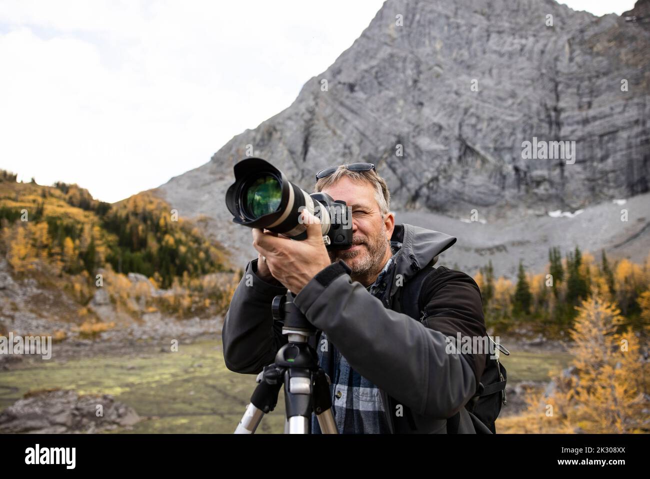 Male photographer with camera below autumn mountain, Canadian Rockies ...