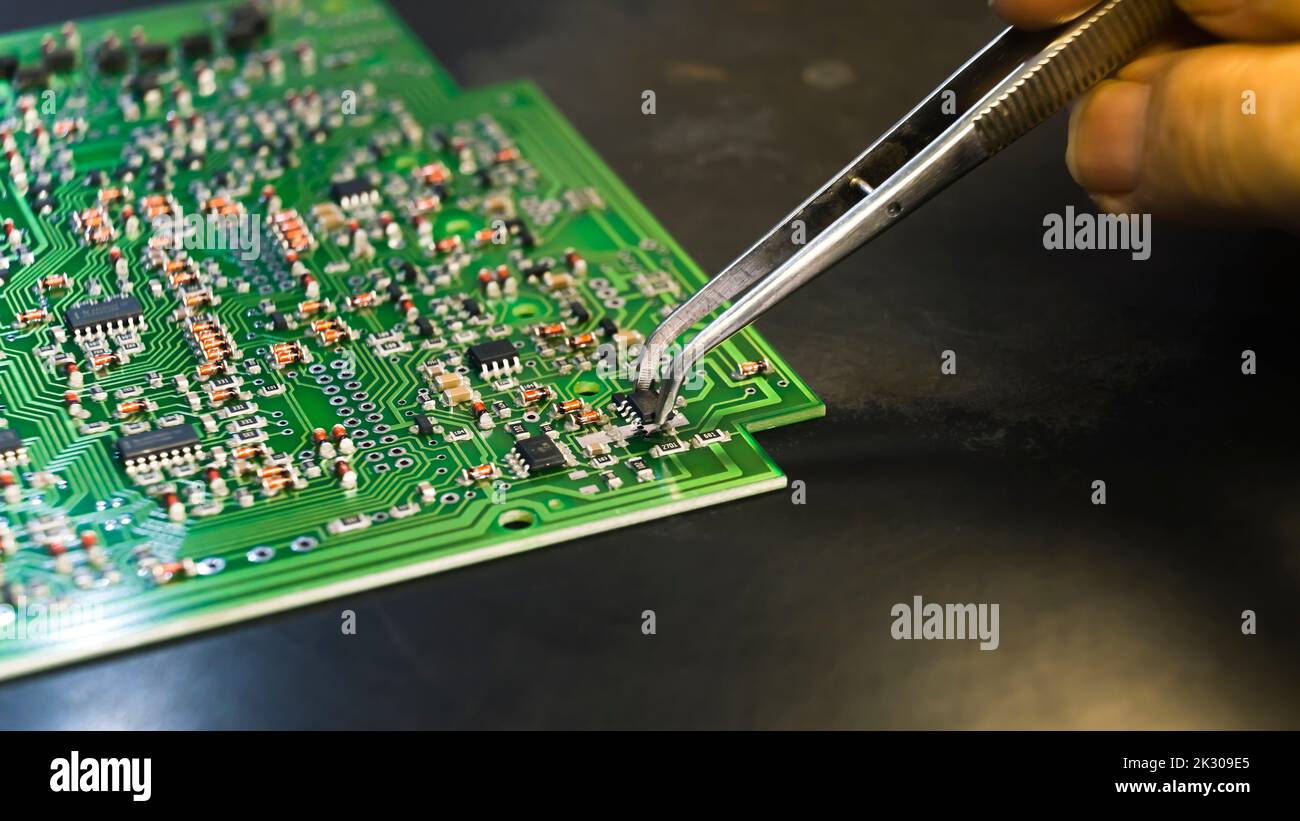 Surface-mount technology concept. Closeup shot of metal tweezers used ...