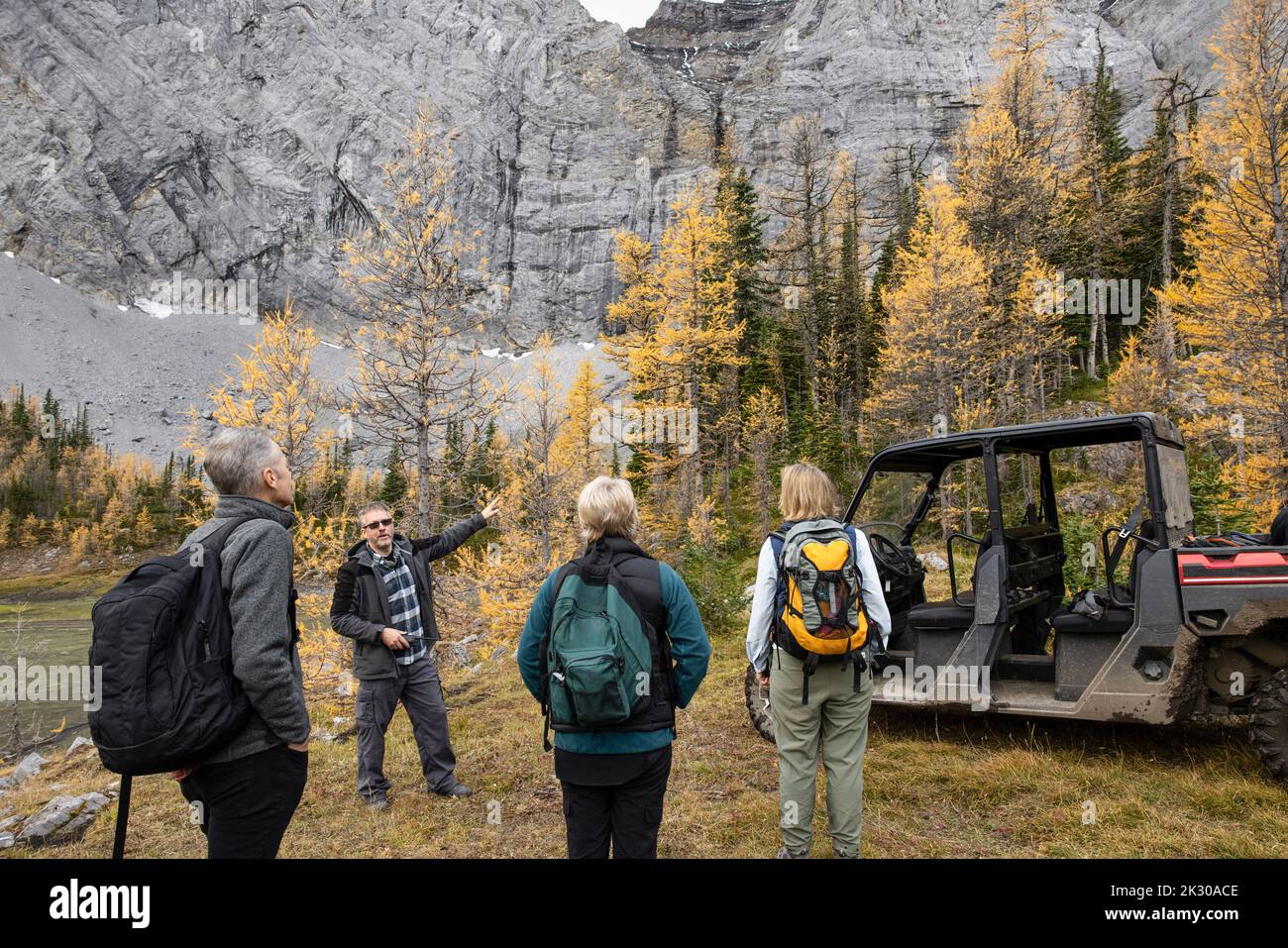 Guide helping hikers below rugged autumn mountain hi-res stock ...