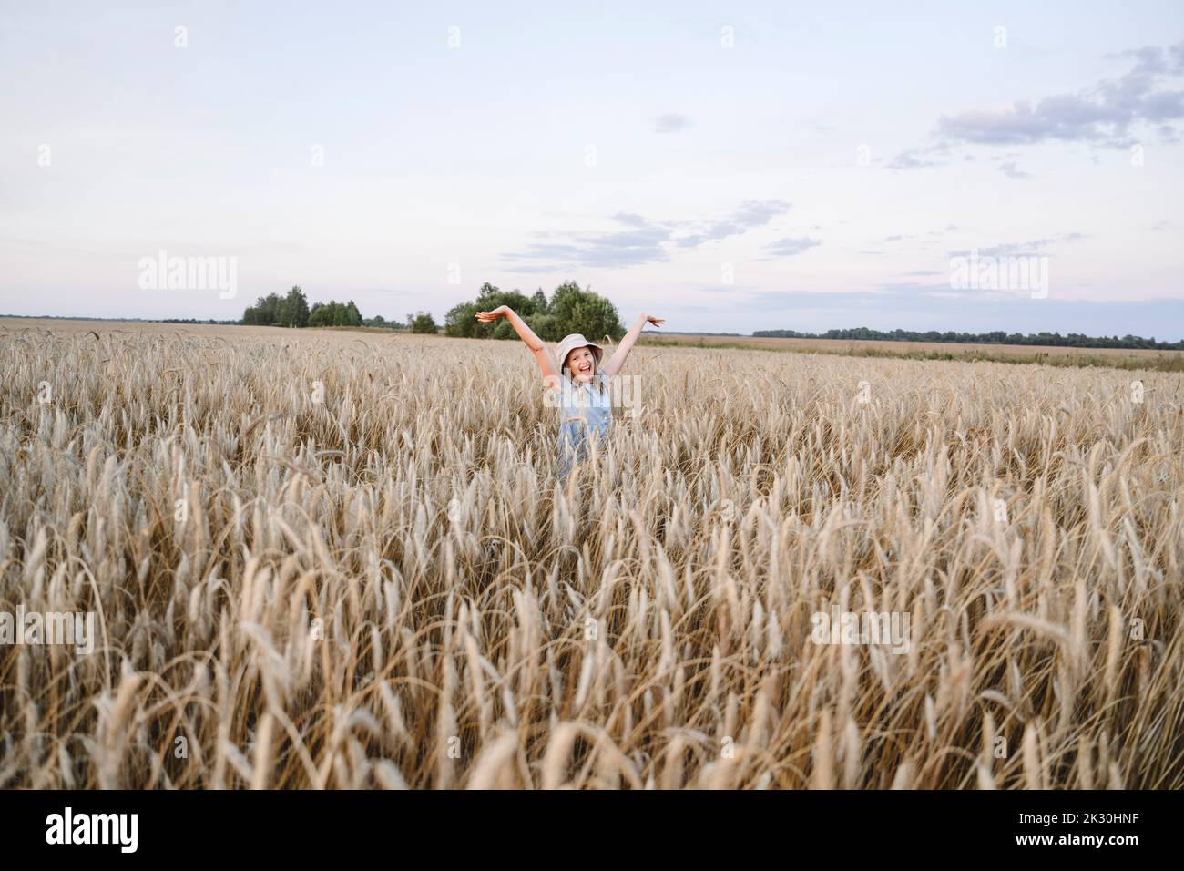 Happy girl with arms raised amidst crops in farm Stock Photo - Alamy