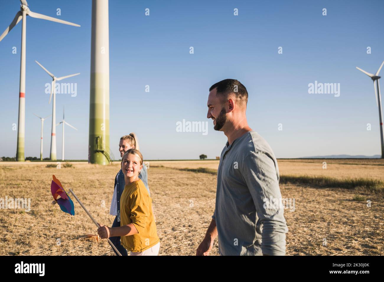 Optimistic family walking in wind park daughter carrying colorful ...