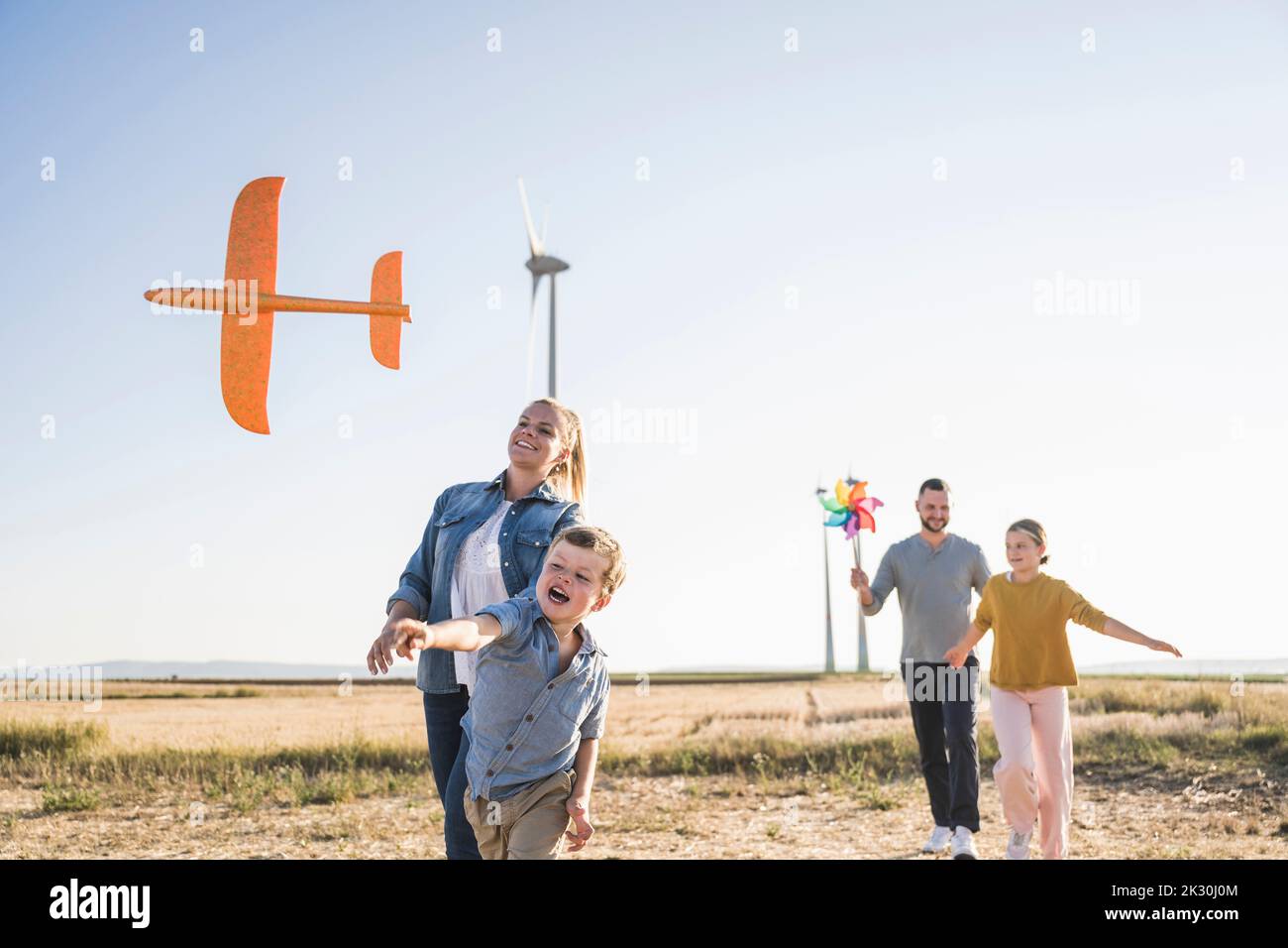 Happy family walking through wind park children carrying toys Stock ...