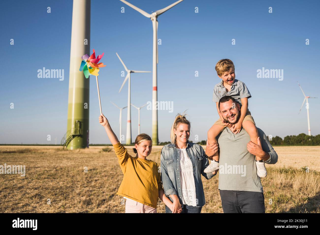 Optimistic family walking in wind park daughter carrying colorful ...