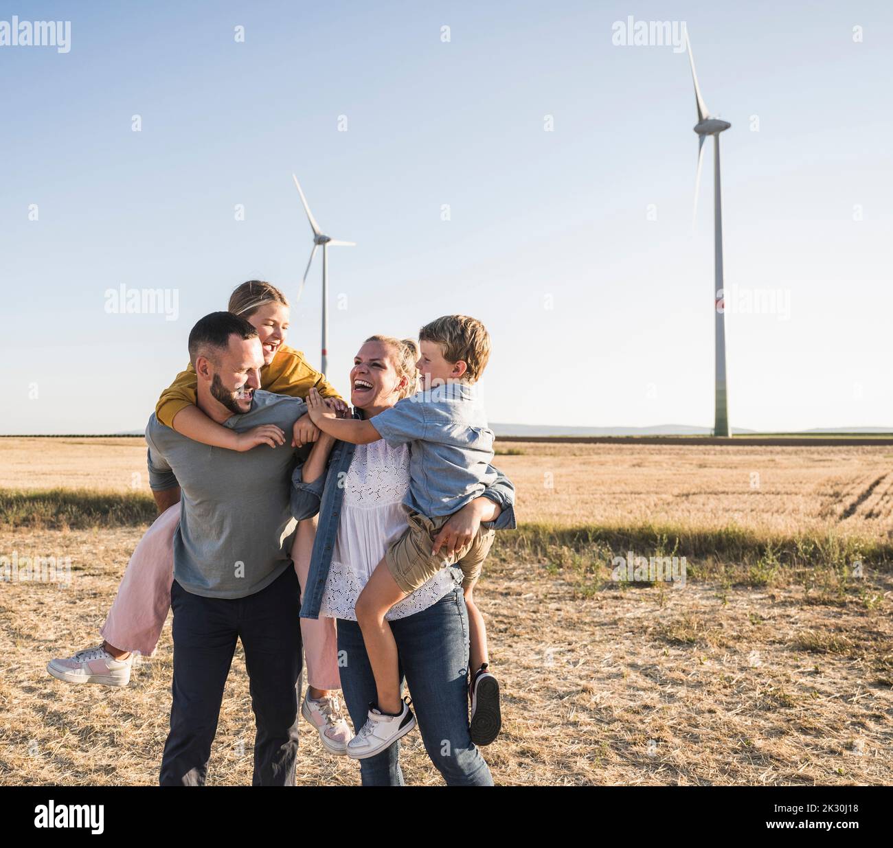 Confident family standing in wind park carrying kids Stock Photo - Alamy