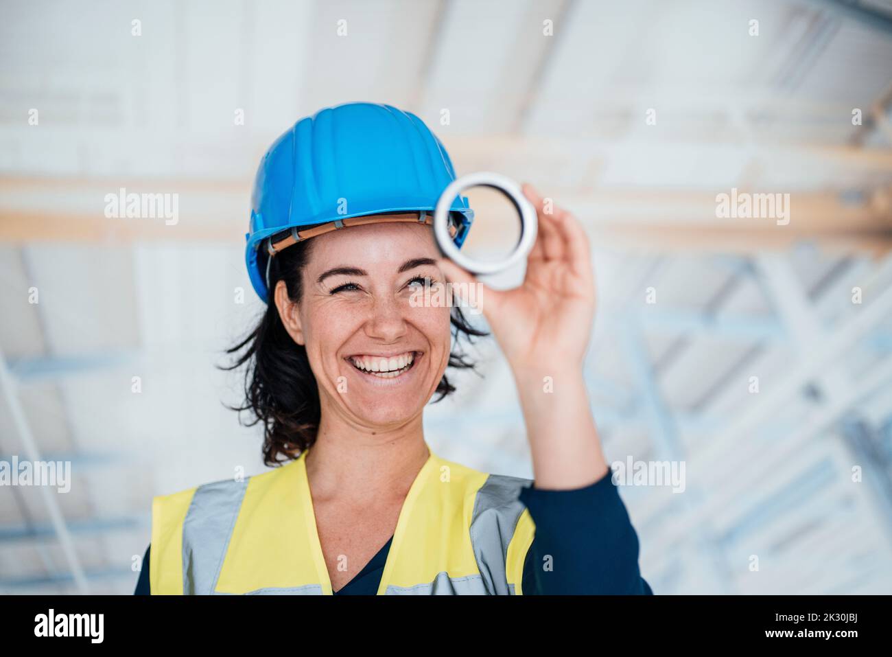 Happy engineer wearing reflective clothing holding ring shape object in ...