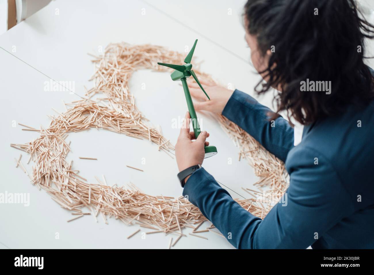 Businesswoman holding wind turbine model above heart shape made from ...