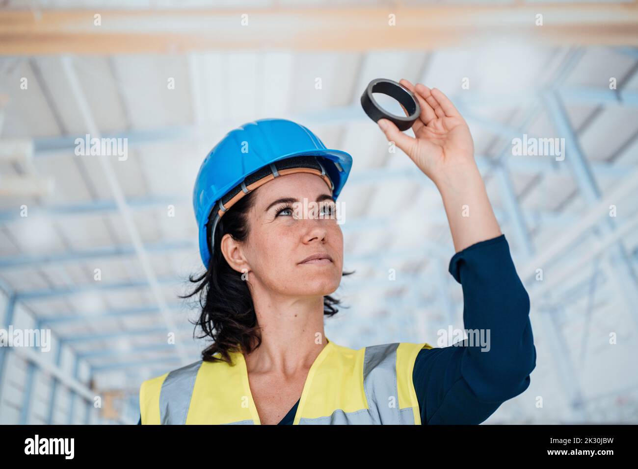 Engineer in reflective clothing looking through ring shape object at ...