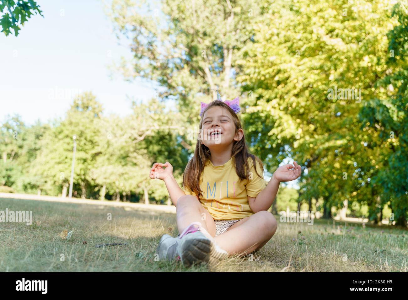 Cheerful girl sitting on grass at park Stock Photo - Alamy