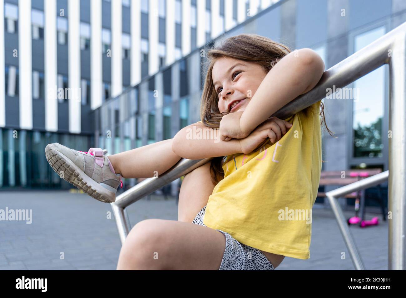 Playful girl climbing on railing at bicycle parking station Stock Photo ...