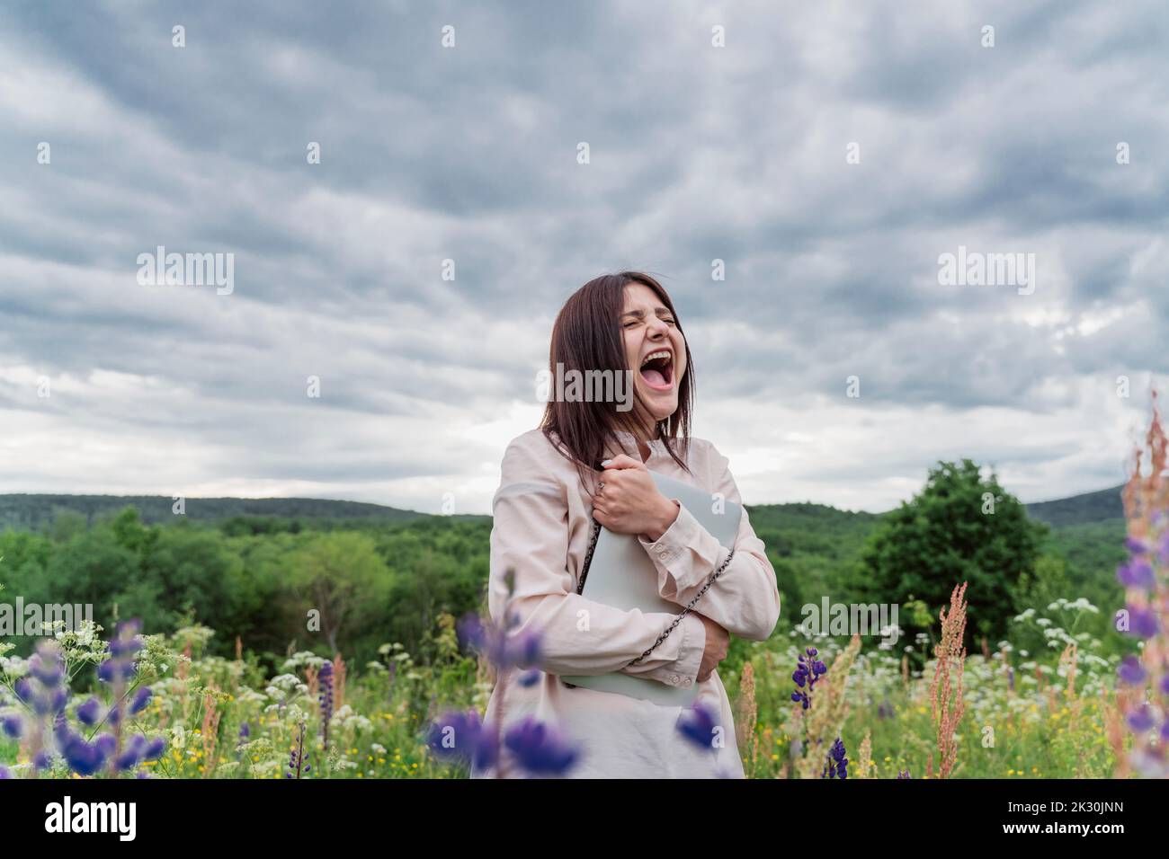 Freelancer with laptop shouting amidst lupine flowers Stock Photo - Alamy