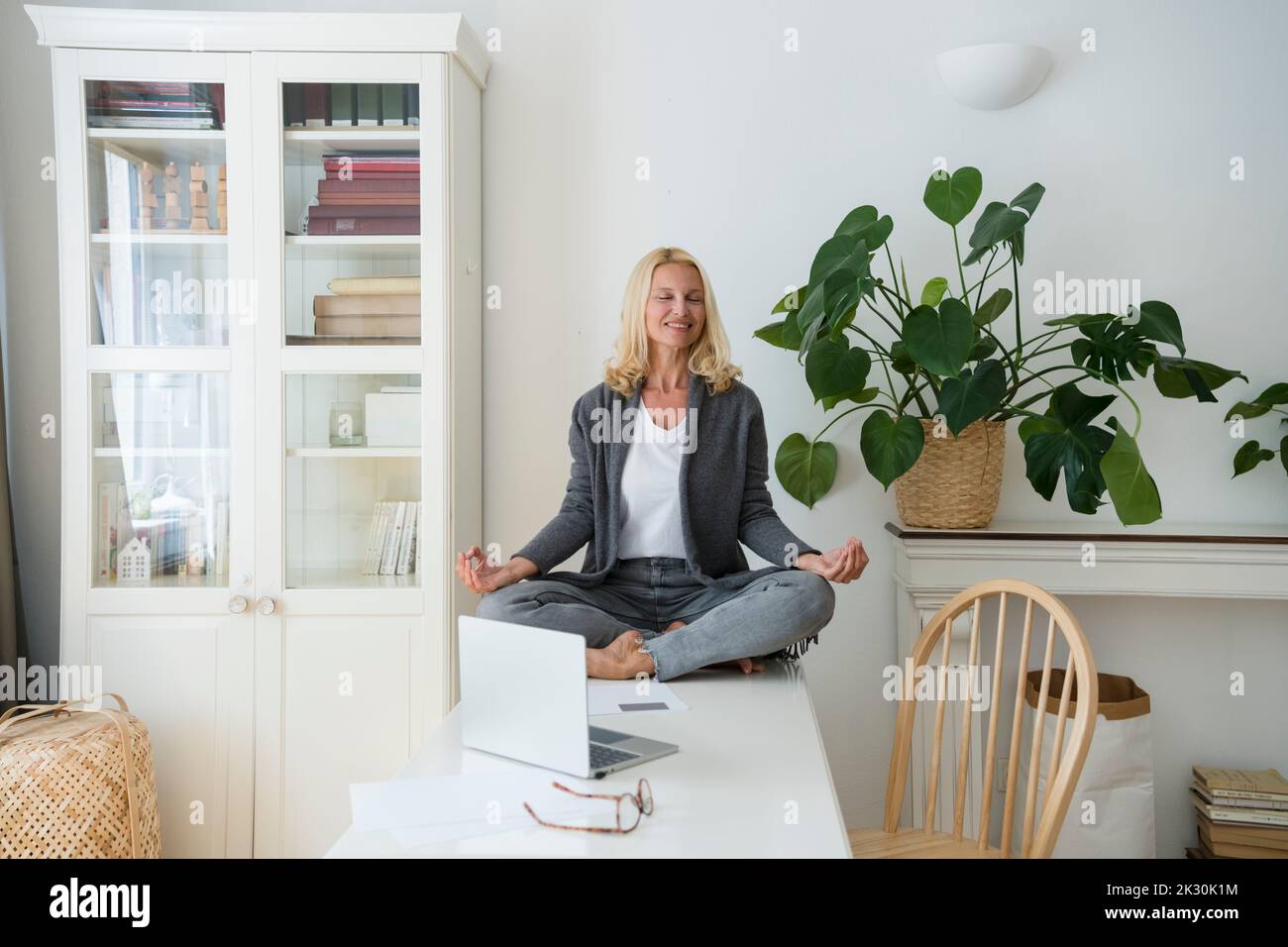 Smiling freelancer with eyes closed meditating on desk in home office ...