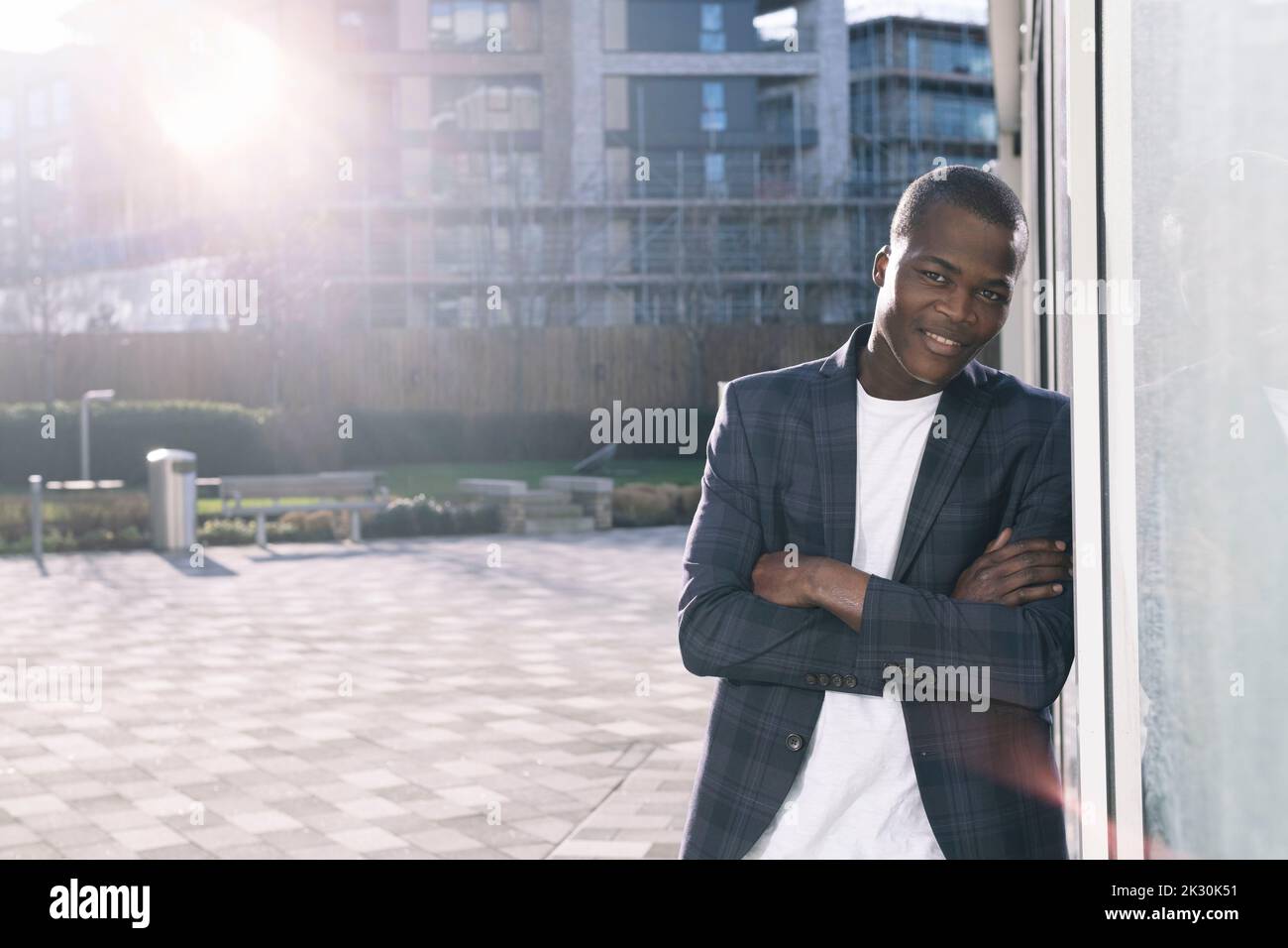 Smiling man with arms crossed leaning on wall Stock Photo - Alamy